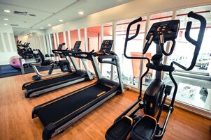 Uma academia com esteiras, elípticos e bolas de exercício.