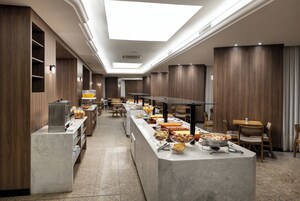 Área de jantar de um hotel moderno, com uma mesa de buffet extensa, painéis de madeira e um claraboia.