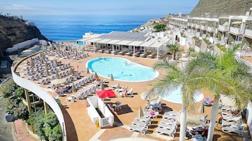 Um resort com uma piscina grande, espreguiçadeiras e vista para o oceano.