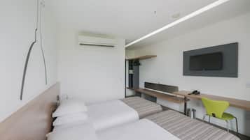 Quarto de hotel moderno com cama, escrivaninha, cadeira, televisão e ar condicionado.