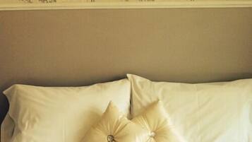Cama com duas almofadas e papel de parede com padrão floral acima.