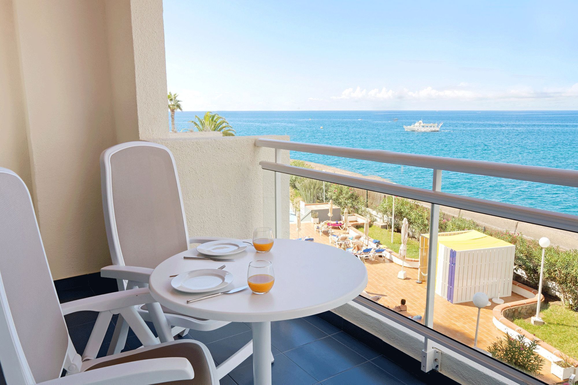 Varanda com mesa posta para dois, com vista para a praia e o mar.