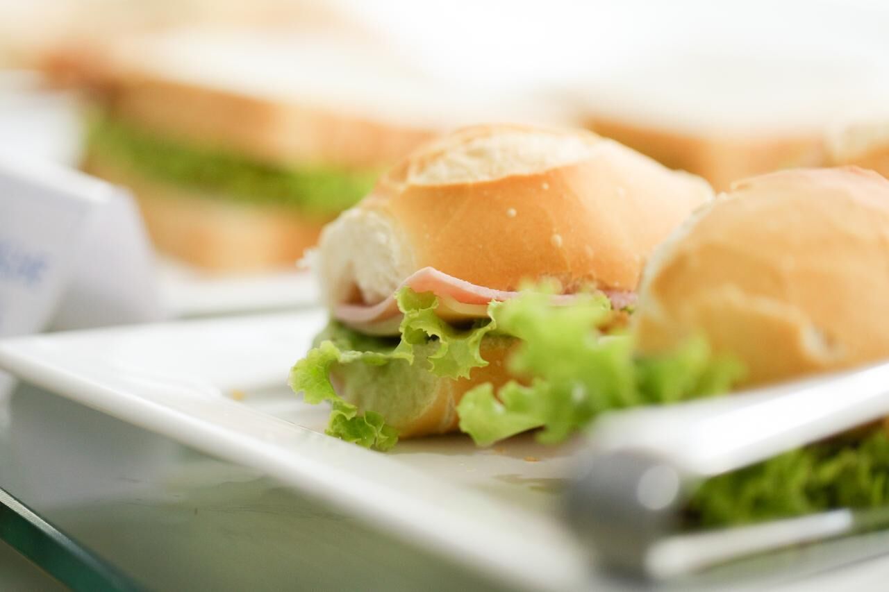Um sanduíche em um prato branco com alface e pão.