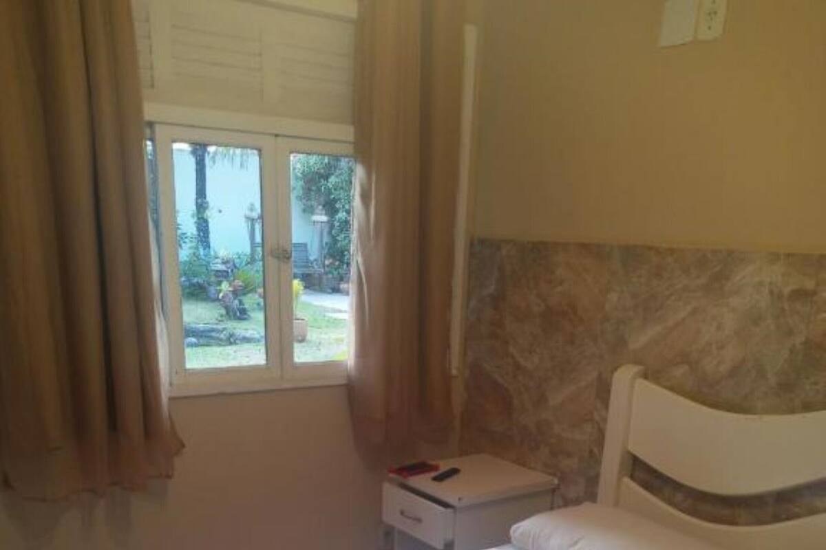 Quarto de hotel com cama, mesa de cabeceira, janela com cortinas e vista para o exterior.