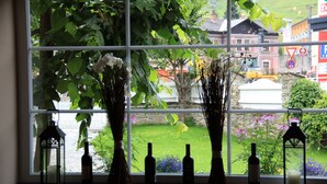 Janela com vista para um jardim, um edifício branco e uma caminhonete amarela.