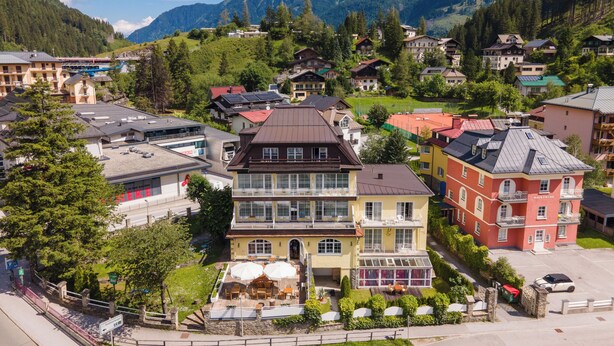 Hotel com amplo espaço de varanda, vários andares e montanhas ao fundo.