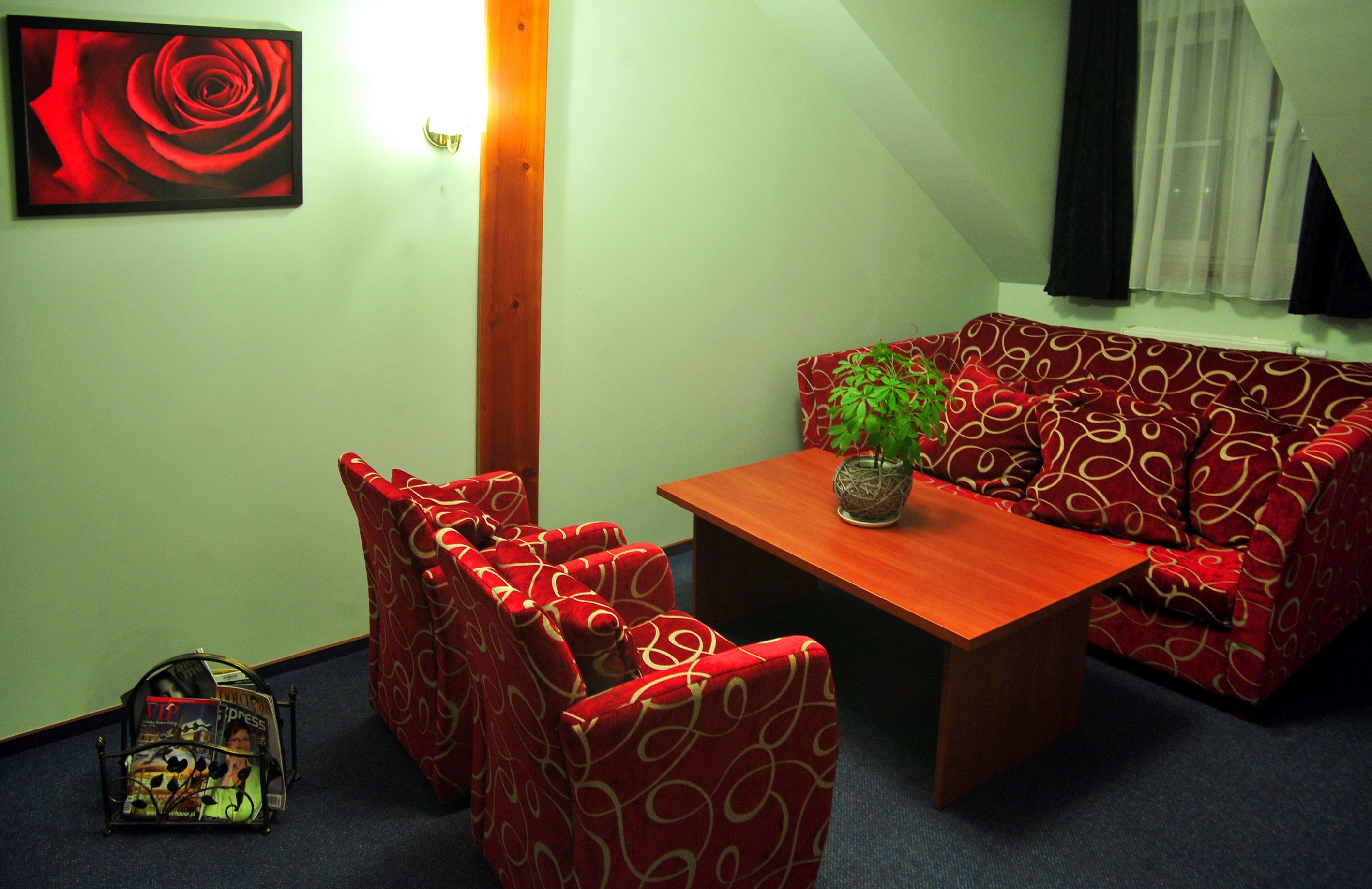 Um quarto com um sofá vermelho estampado, uma mesa de centro de madeira e um porta-revistas.