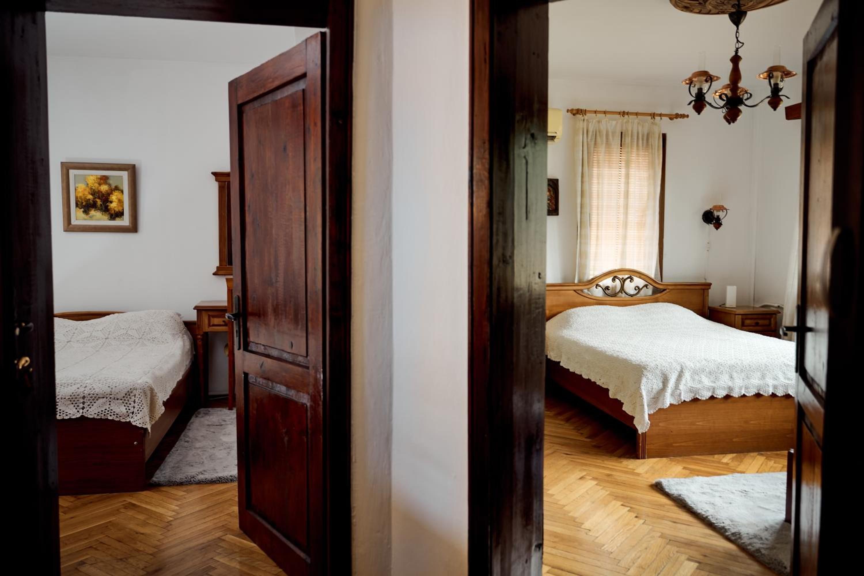 Quarto com cama de madeira, mesa de cabeceira, luminária e pintura na parede.