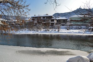 Bairro residencial com uma casa grande, um lago e paisagem coberta de neve.