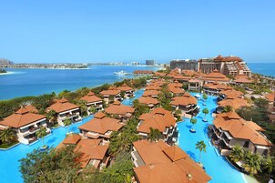Um resort com várias piscinas rodeado por villas com telhados em tijolos vermelhos, com vista para o mar azul e límpido.
