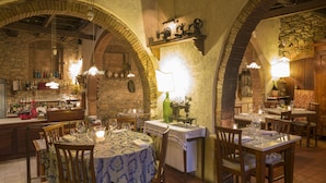 Uma área de jantar rústica com paredes de pedra, mesas de madeira e luminárias pendentes.