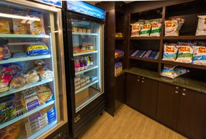 Vitrine refrigerada com diversos alimentos e uma prateleira cheia de pacotes de batatas.