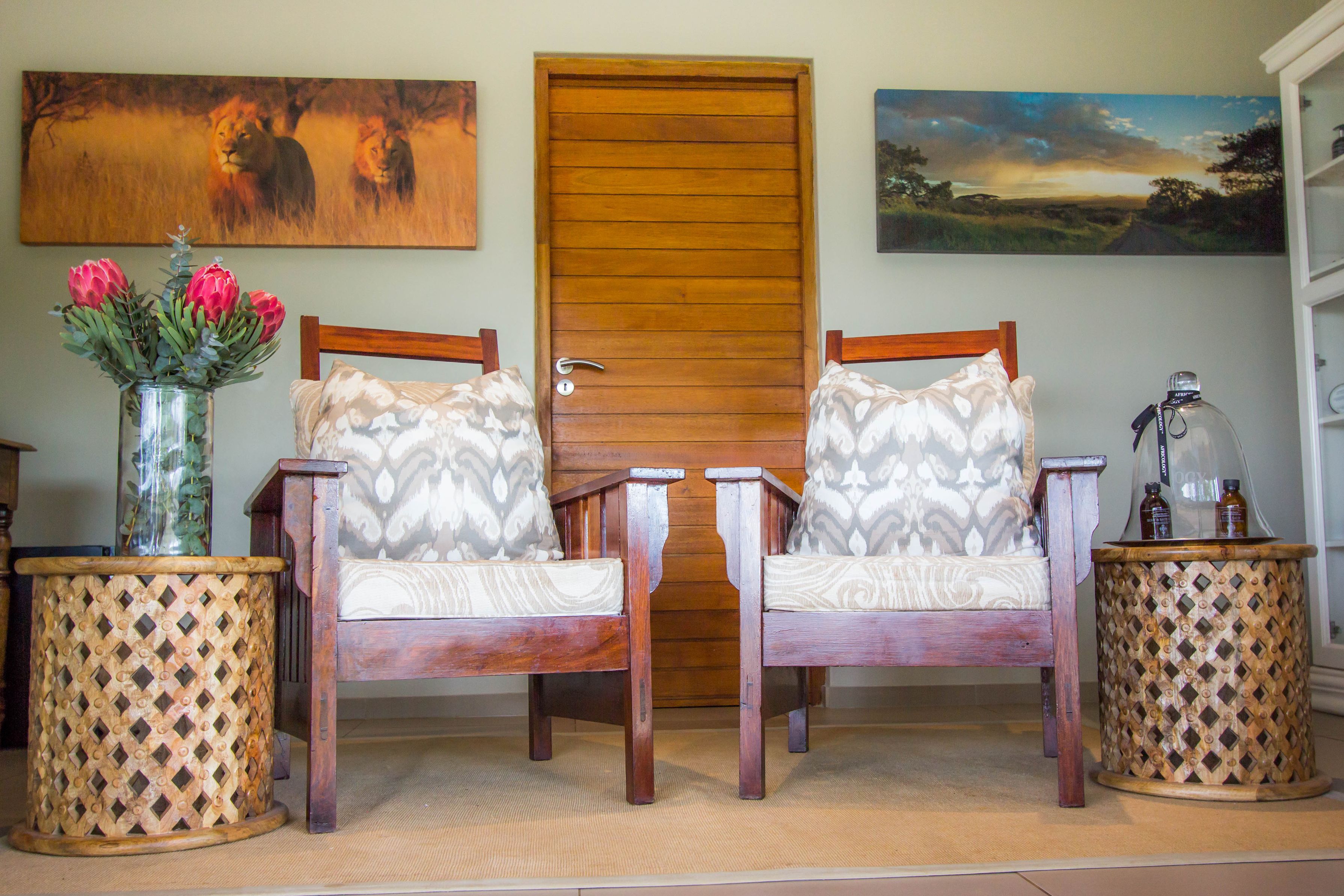 Um quarto com duas cadeiras de madeira, uma porta de madeira e um quadro na parede.