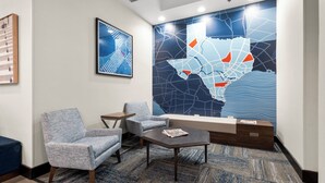 Um hall com duas poltronas, uma mesa de centro, um mural de mapa e um banco de madeira.