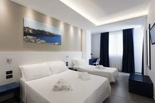 Quarto de hotel com duas camas, uma escrivaninha, uma cadeira, um quadro e uma televisão.