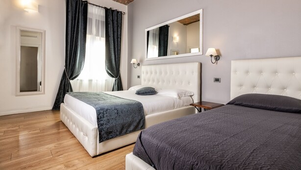 Quarto com duas camas, um espelho grande e teto de madeira.