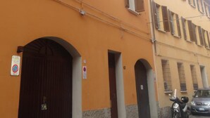 Um edifício com várias portas e janelas, algumas com persianas, e uma motocicleta estacionada.