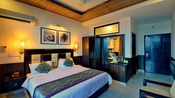 Quarto de hotel com cama grande, mesas de cabeceira, escrivaninha, espelho e guarda-roupa.