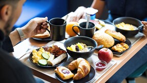 Bandeja de café da manhã com diversos alimentos, incluindo ovos, bacon, torradas e frutas.