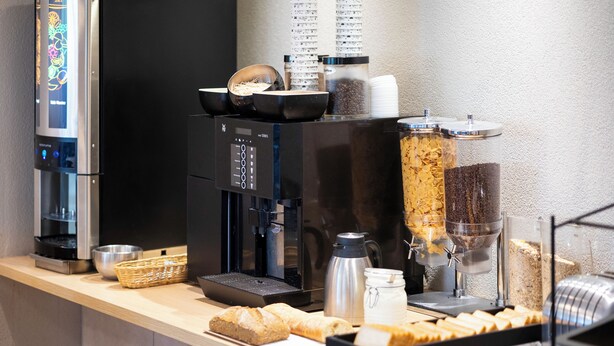 Uma estação de café com uma máquina de café, cafeteiras e diversos tipos de grãos.