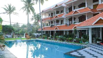 Hotel com piscina, várias varandas e vegetação exuberante.