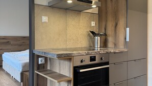 Uma cozinha compacta com forno embutido, um armário de madeira e um fogão moderno.