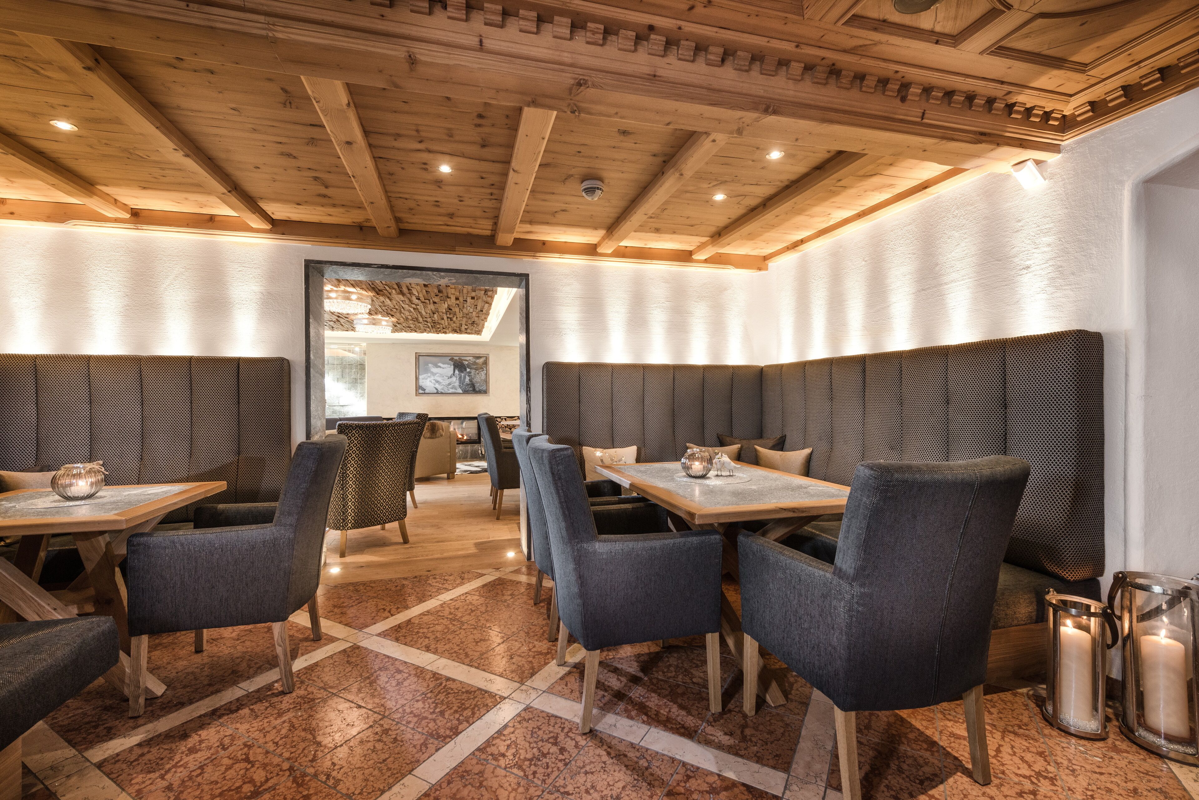 Um restaurante com cabines e mesas, vigas de madeira no teto e piso de azulejos.
