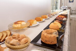 Buffet com diversos produtos de panificação, incluindo bolos, doces e pão.