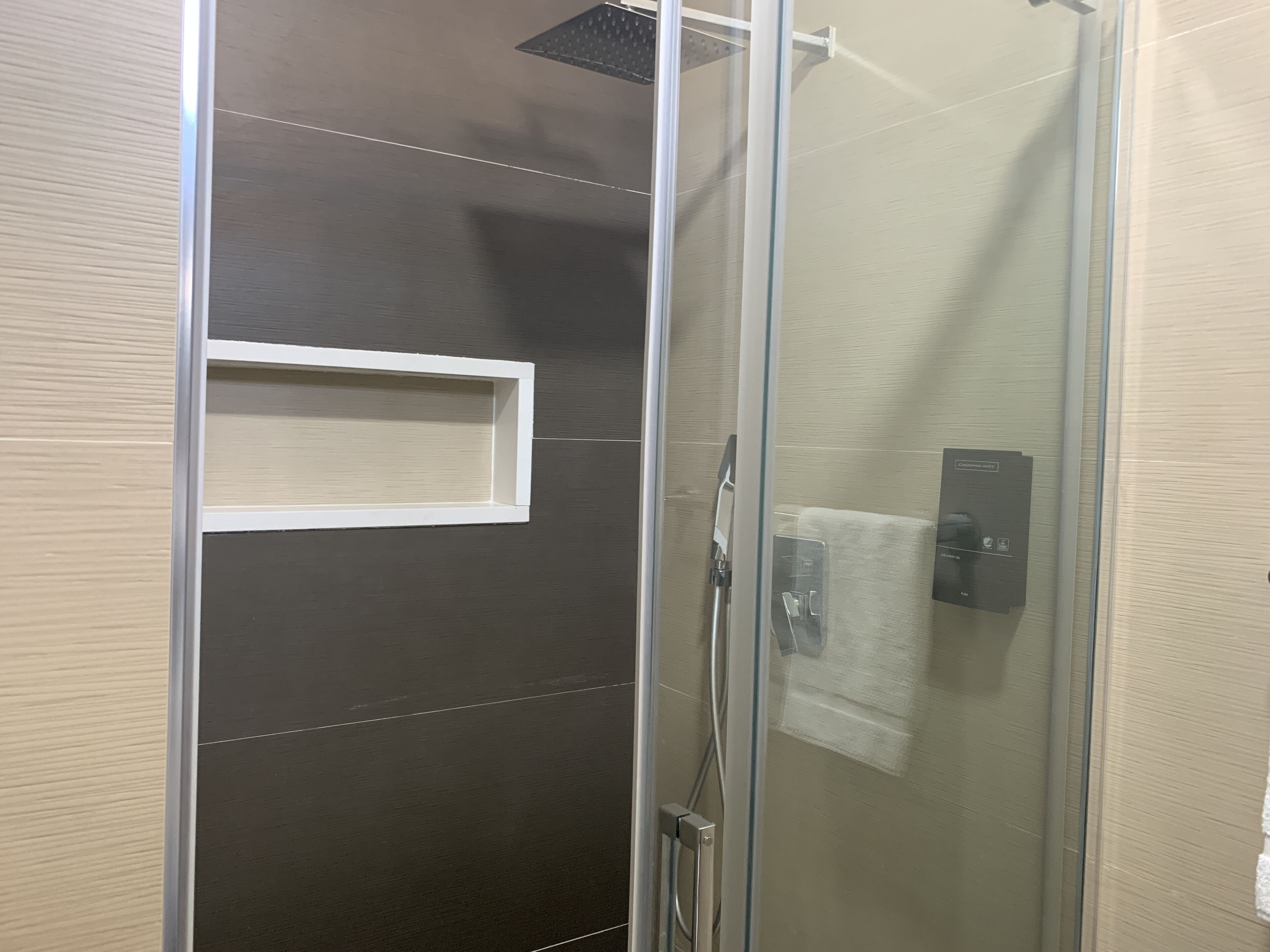 Uma área de chuveiro moderna com porta de vidro, porta-toalhas e painel de controle.