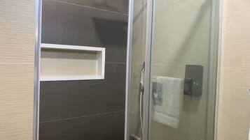 Uma área de chuveiro moderna com porta de vidro, porta-toalhas e painel de controle.