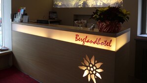 Uma receção de hotel com um cartaz de vista para as montanhas, uma planta e um sinal a indicar "Berslandhotel".