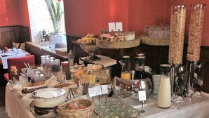 Uma mesa de buffet com diversos alimentos, incluindo pão, doces e acompanhamentos.