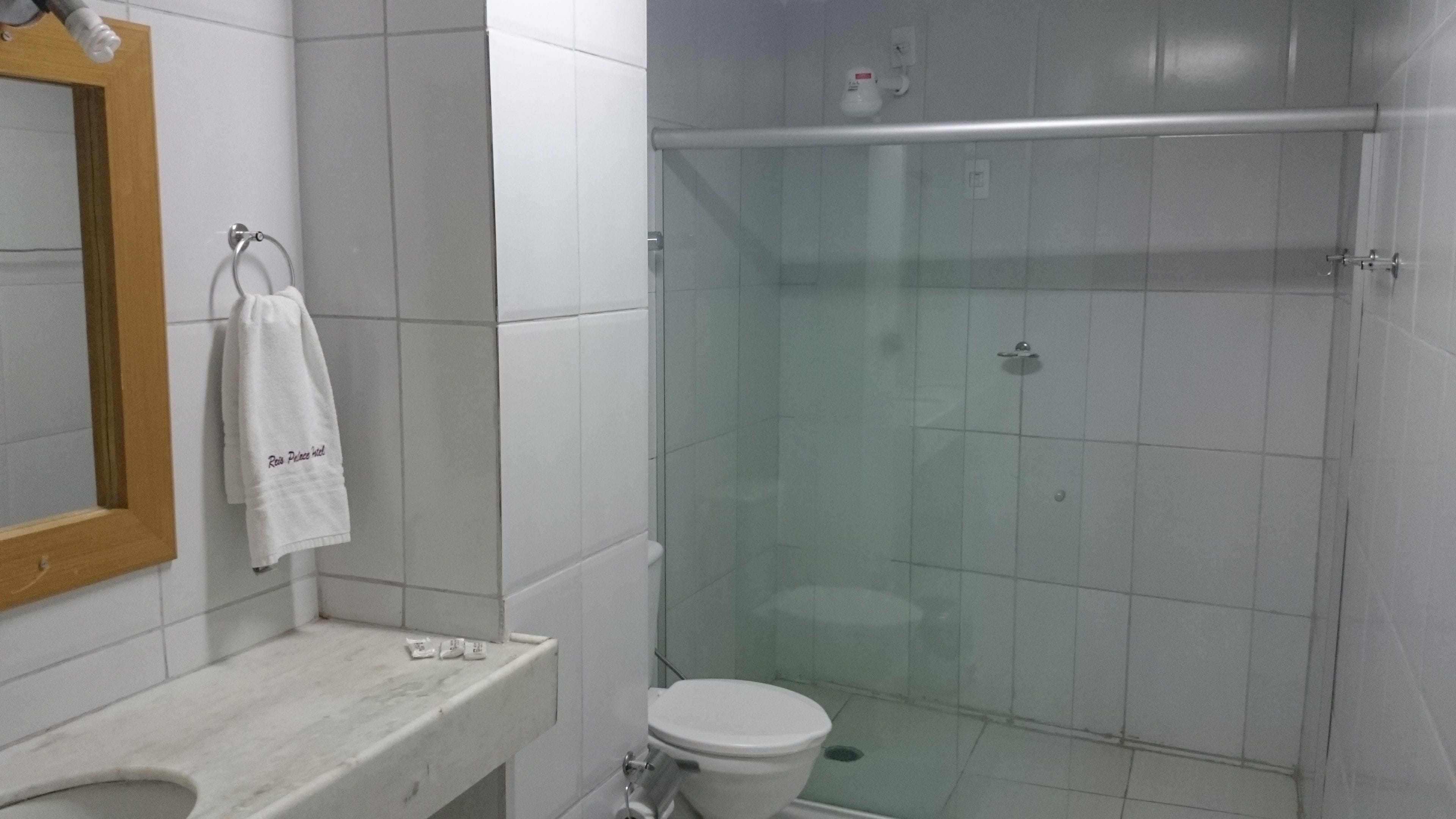 Casa de banho com cabine de duche em vidro, sanita e lavatório de mármore.