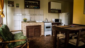 Uma cozinha com fogão de tijolos, armários brancos, micro-ondas e uma área de refeições com mesa e cadeiras.