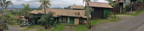 Uma casa tradicional com telhado em telhas, fachada verde e pequena varanda.