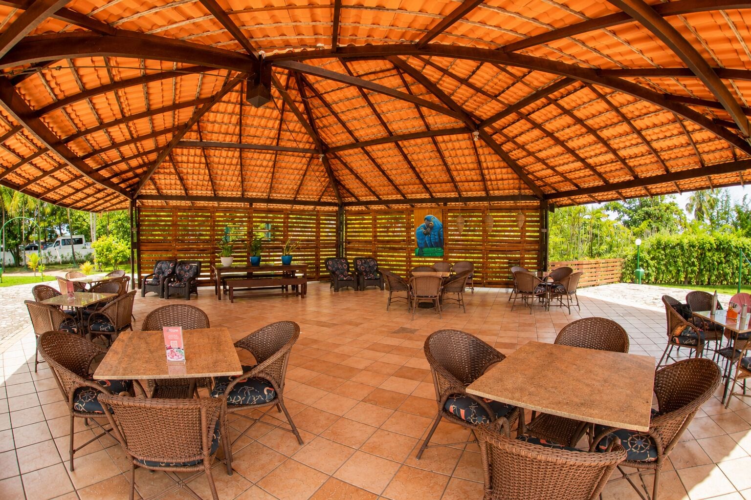 Um pátio ao ar livre com piso de azulejos, móveis de vime e uma estrutura de pérgola de madeira.