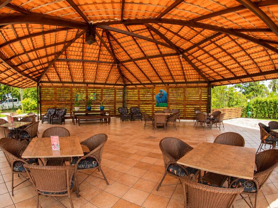 Um pátio ao ar livre com piso de azulejos, móveis de vime e uma estrutura de pérgola de madeira.