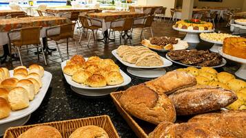 Buffet com diversos pães e pastelaria.