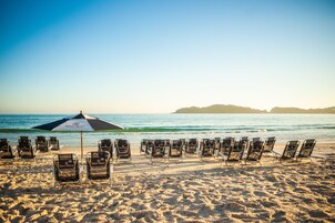 Na praia, espreguiçadeiras, guarda-sóis de praia, toalhas de praia 