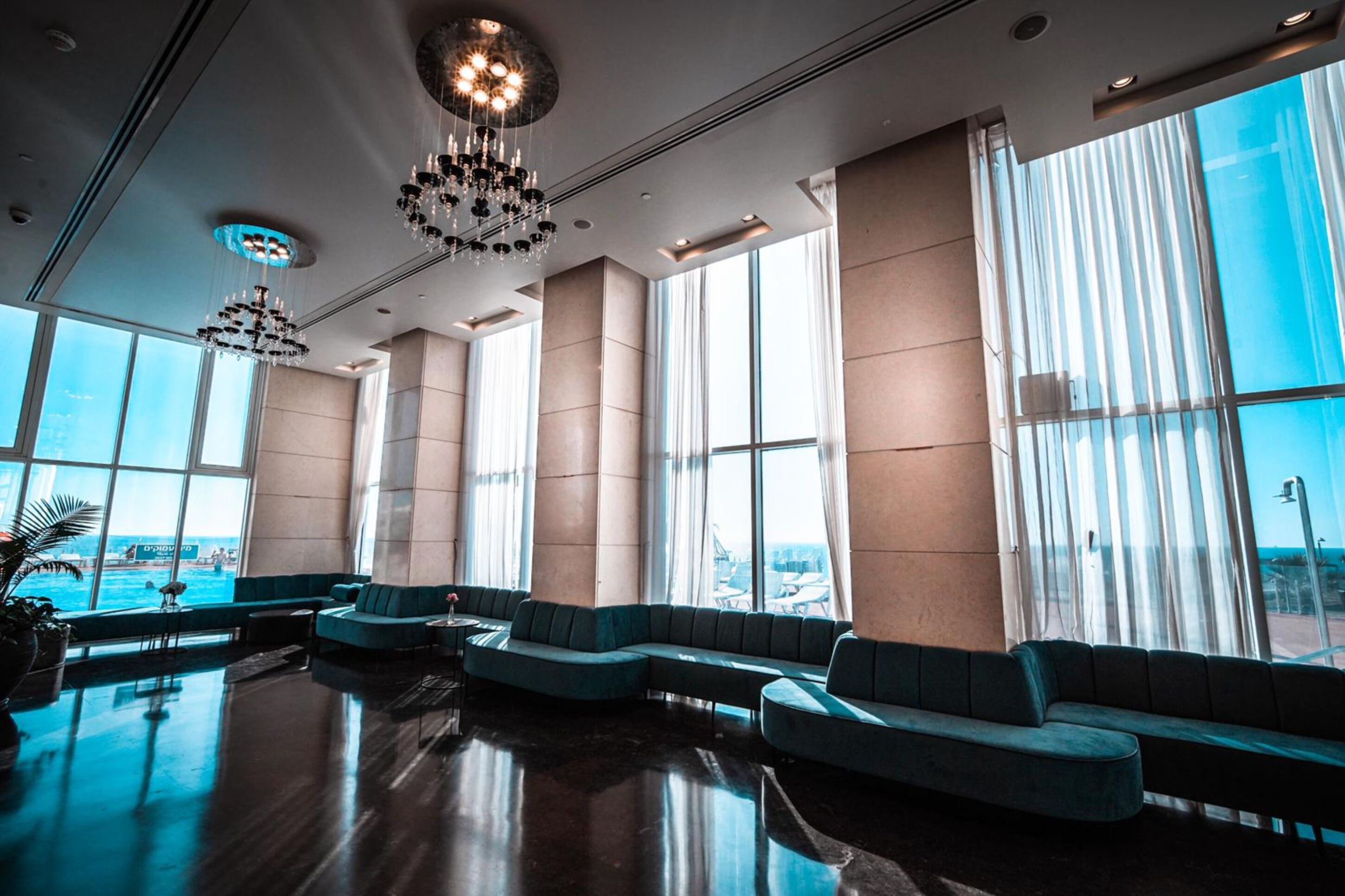 Um lobby moderno com janelas amplas, área de estar em curva e luminárias decorativas.