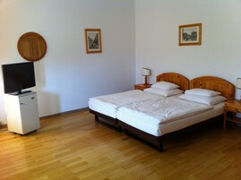 Quarto com uma cama, uma TV sobre um móvel e duas molduras na parede.