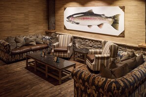 Uma sala de estar acolhedora com sofás estampados, uma mesa de centro e um grande mural de peixes na parede.