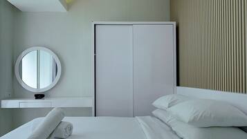 Quarto de hotel moderno com cama, um espelho redondo, guarda-roupa e luminária fixada na parede.