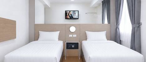 Quarto de hotel com duas camas, televisão na parede e janela com cortinas.