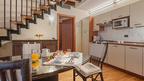 Cozinha moderna com área de jantar, incluindo escada, armários de madeira, micro-ondas e mesa posta para o café da manhã.