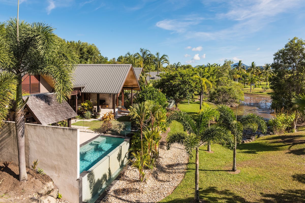 Um resort moderno com piscina, vegetação exuberante e vista para uma cordilheira.