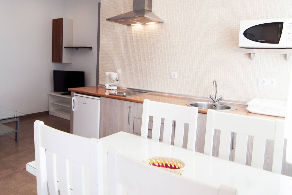 Uma cozinha moderna com micro-ondas, pia e área de refeições com mesa e cadeiras.