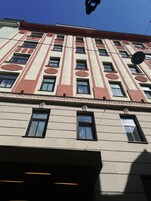 Um edifício de vários andares com fachada simétrica, com janelas retangulares e detalhes decorativos em tijolo.