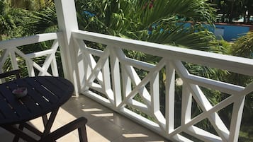 Uma varanda com guarda-corrimão branco, uma mesa preta e uma cadeira vermelha.