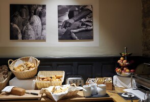 Buffet de café da manhã com pães, bolos e frutas.
